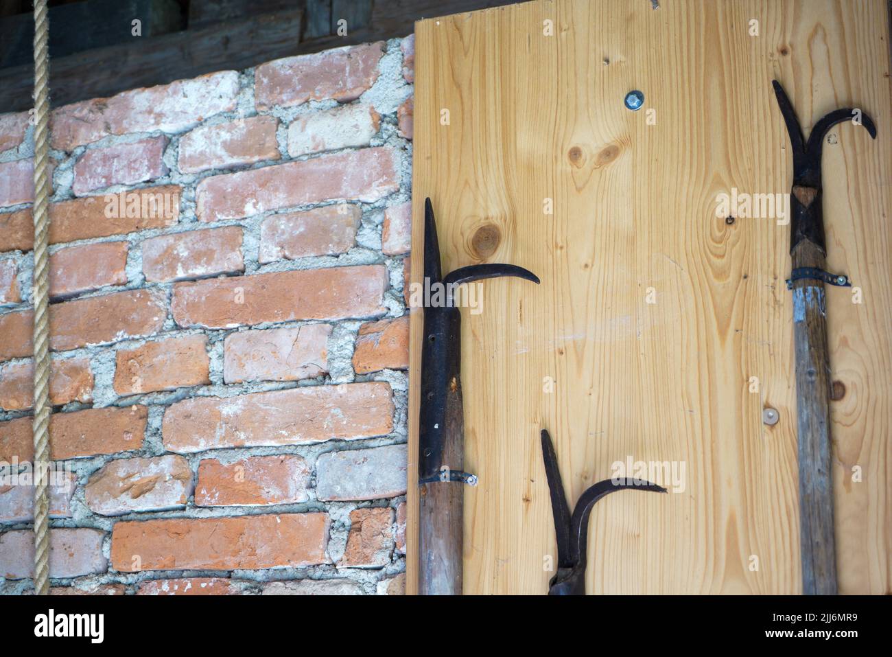 A closeup of the heads of a short firefighter pike pole hanging on a ...