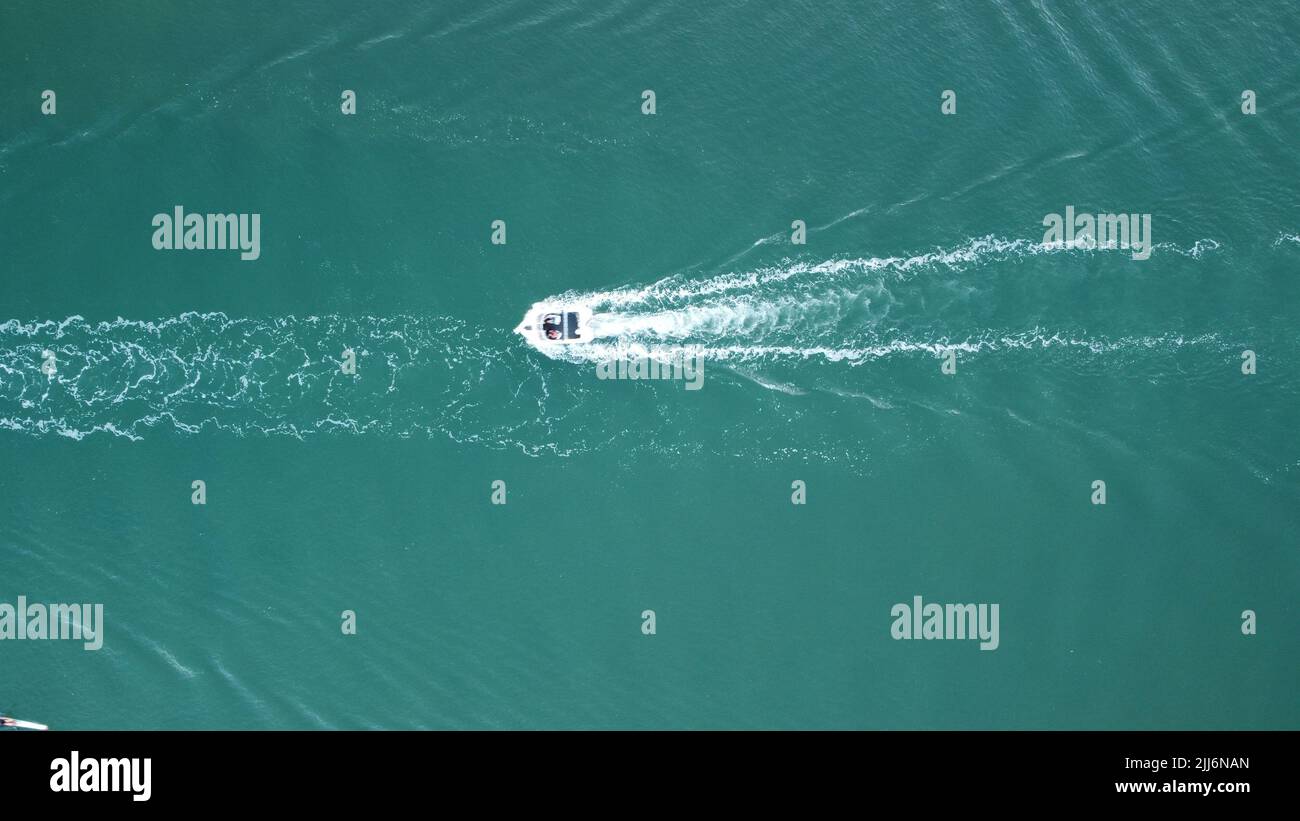An aerial view of a motor boat floating in the ocean and leaving a ...