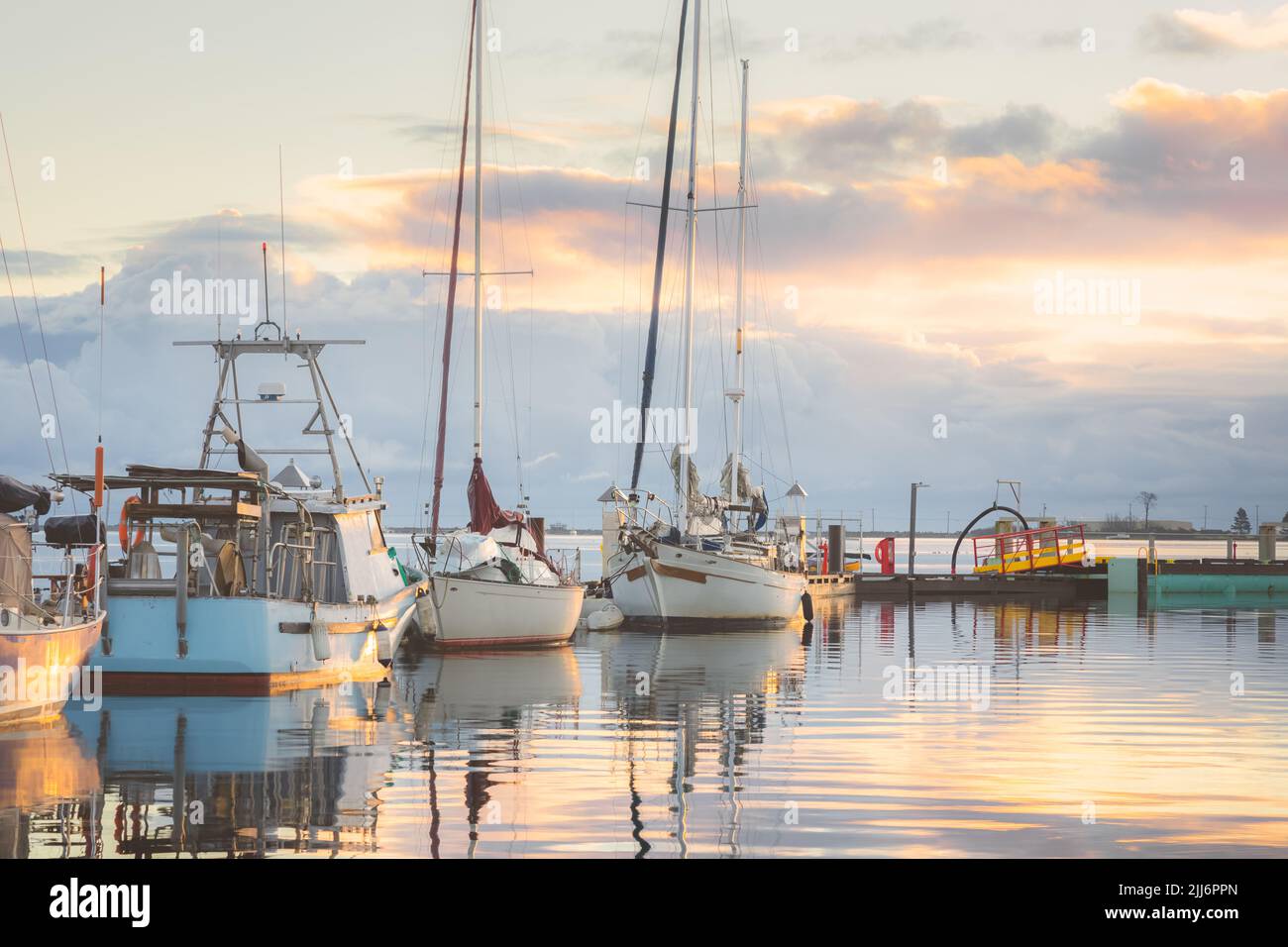 Calm, peaceful golden sunset or sunrise over boats and dock at Comox ...