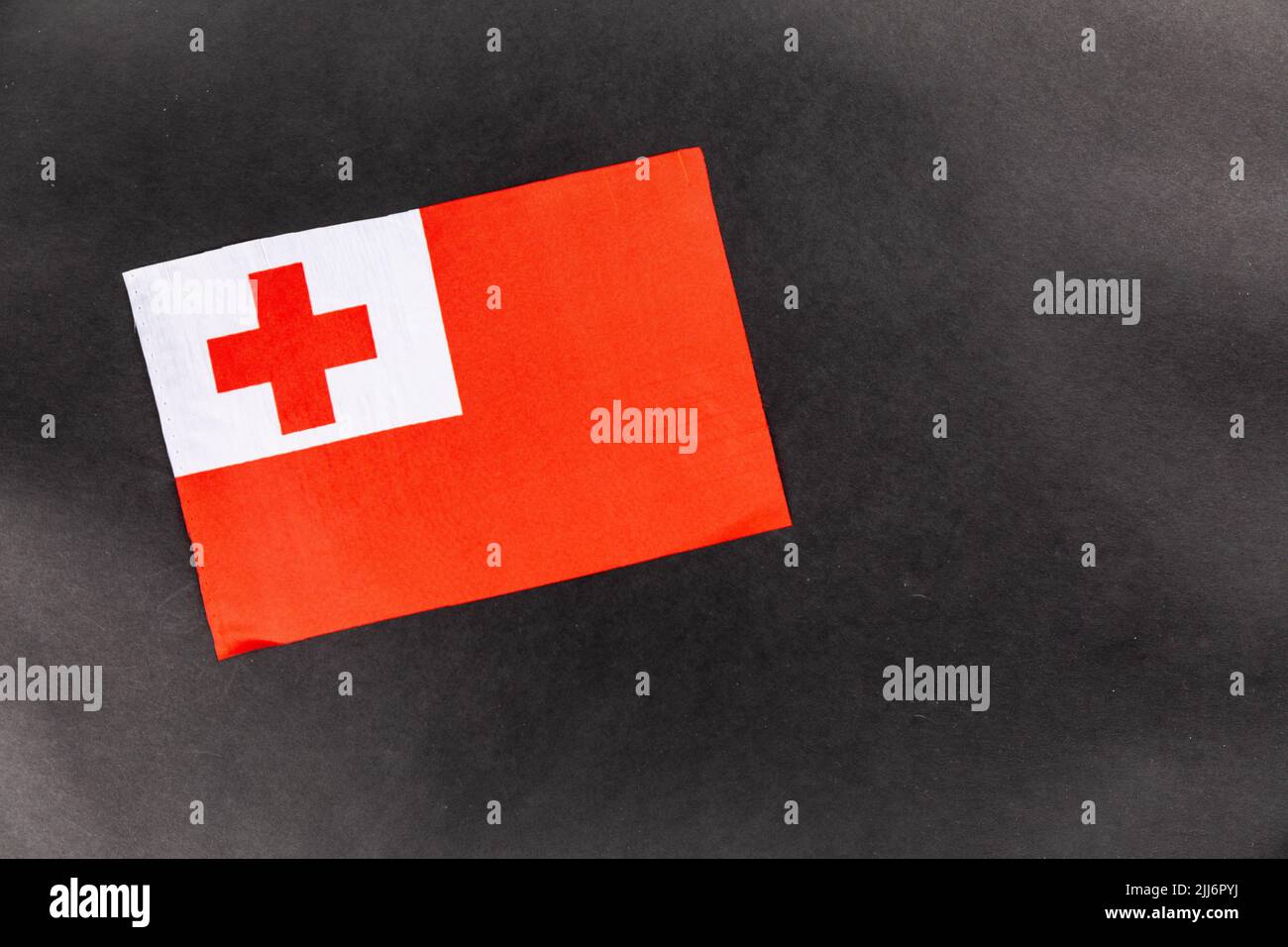 A close-up shot of the flag of Tonga on a dark background with copy ...