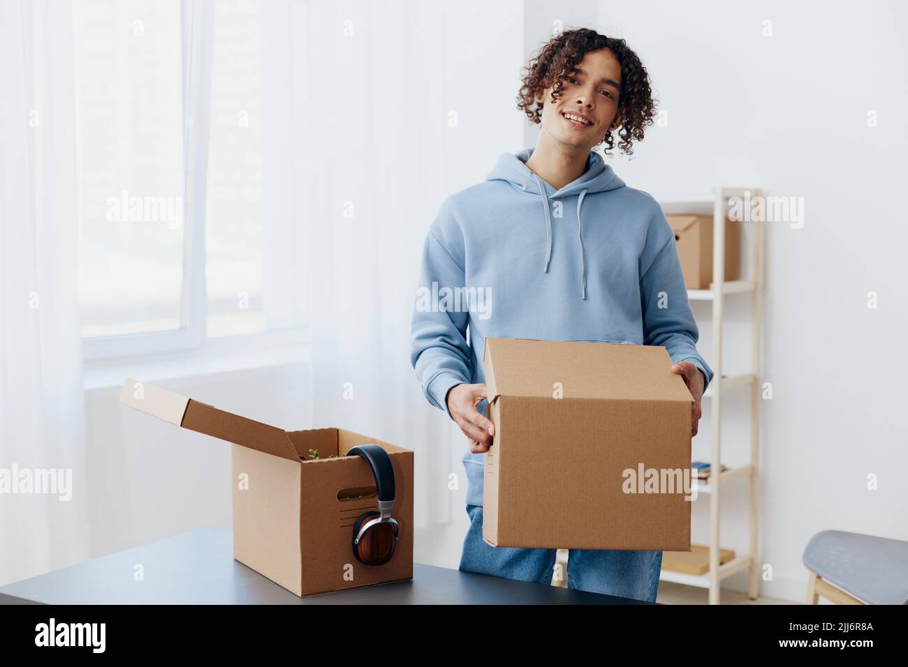 A young man unpacking things from boxes in the room interior Stock ...