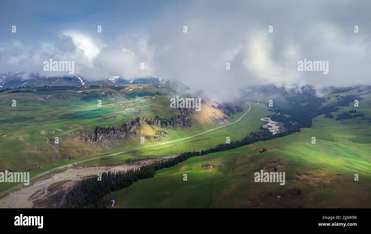 A beautiful landscape with green fields snow capped mountains and gray ...