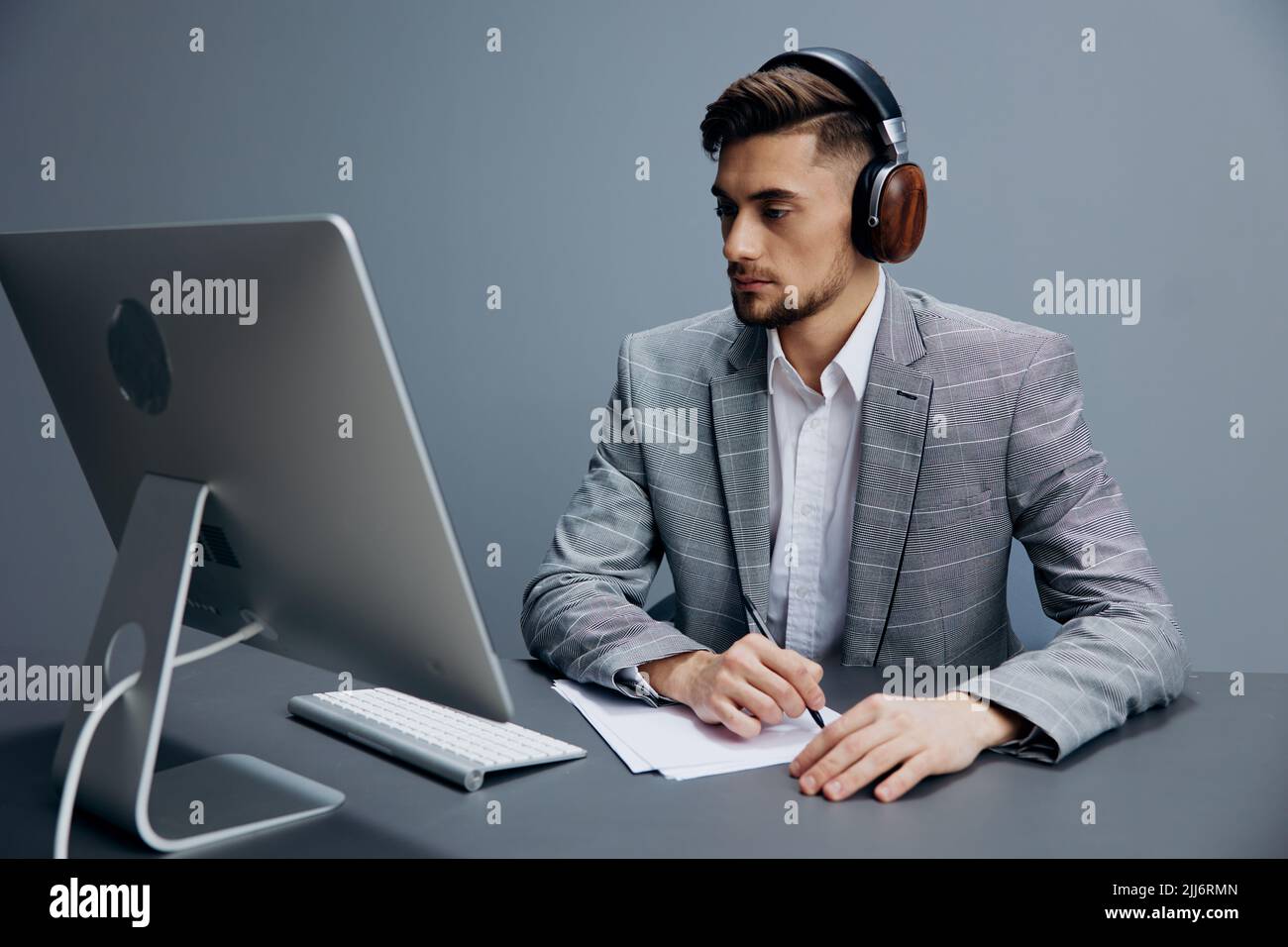businessmen in headphones in a gray suit sits in front of a computer ...