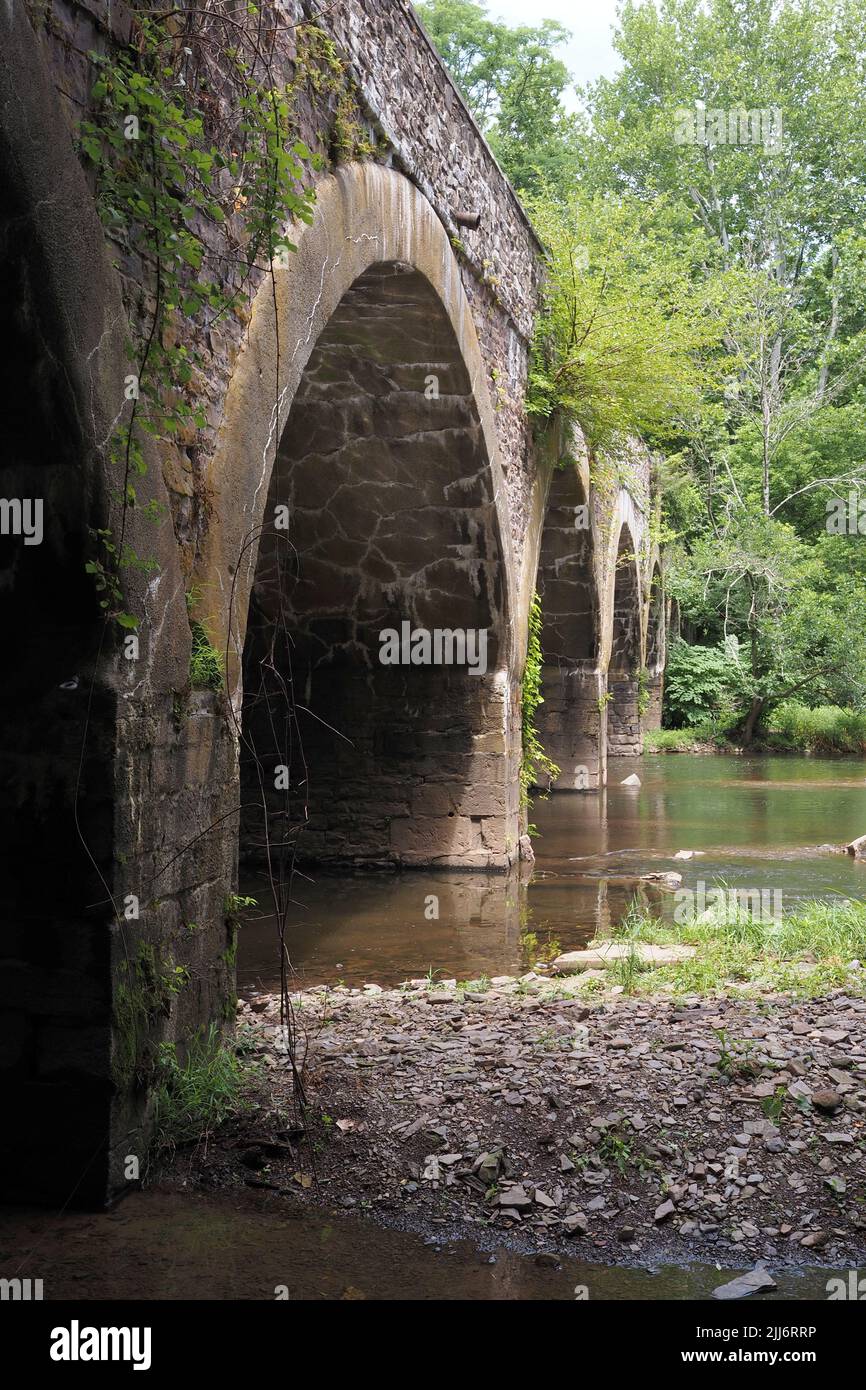 Old stone bridge over water in green deciduous park Stock Photo - Alamy