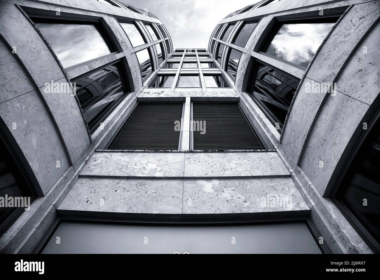 A low angle of a high modern building with big windows in greyscale ...