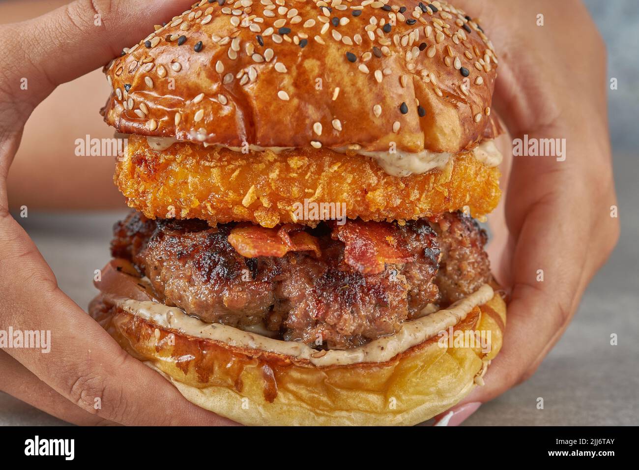 A mans hand holding a meat burger Stock Photo - Alamy
