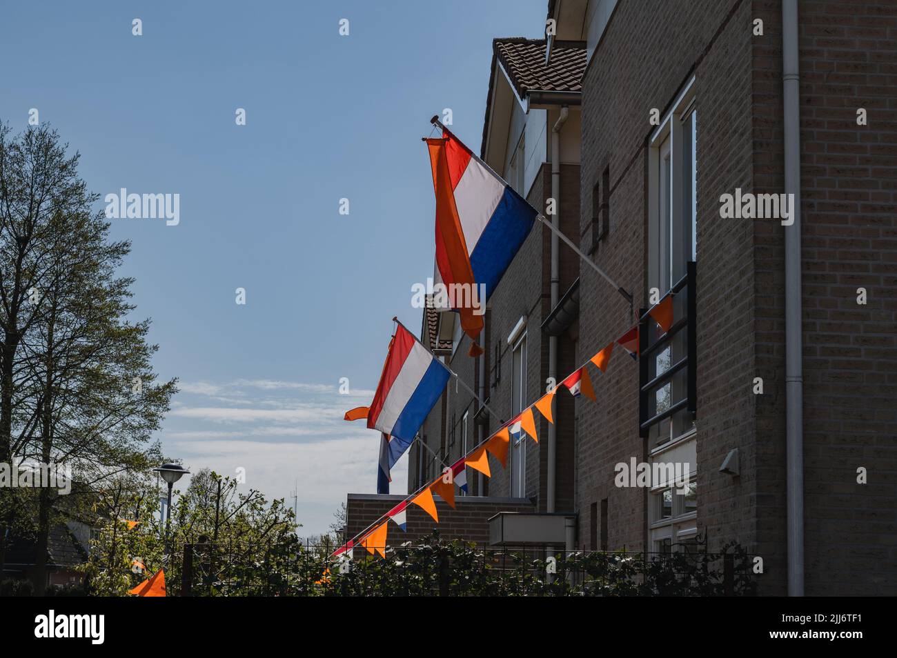 The flags of Netherlands hanging from the exterior of a building over a ...