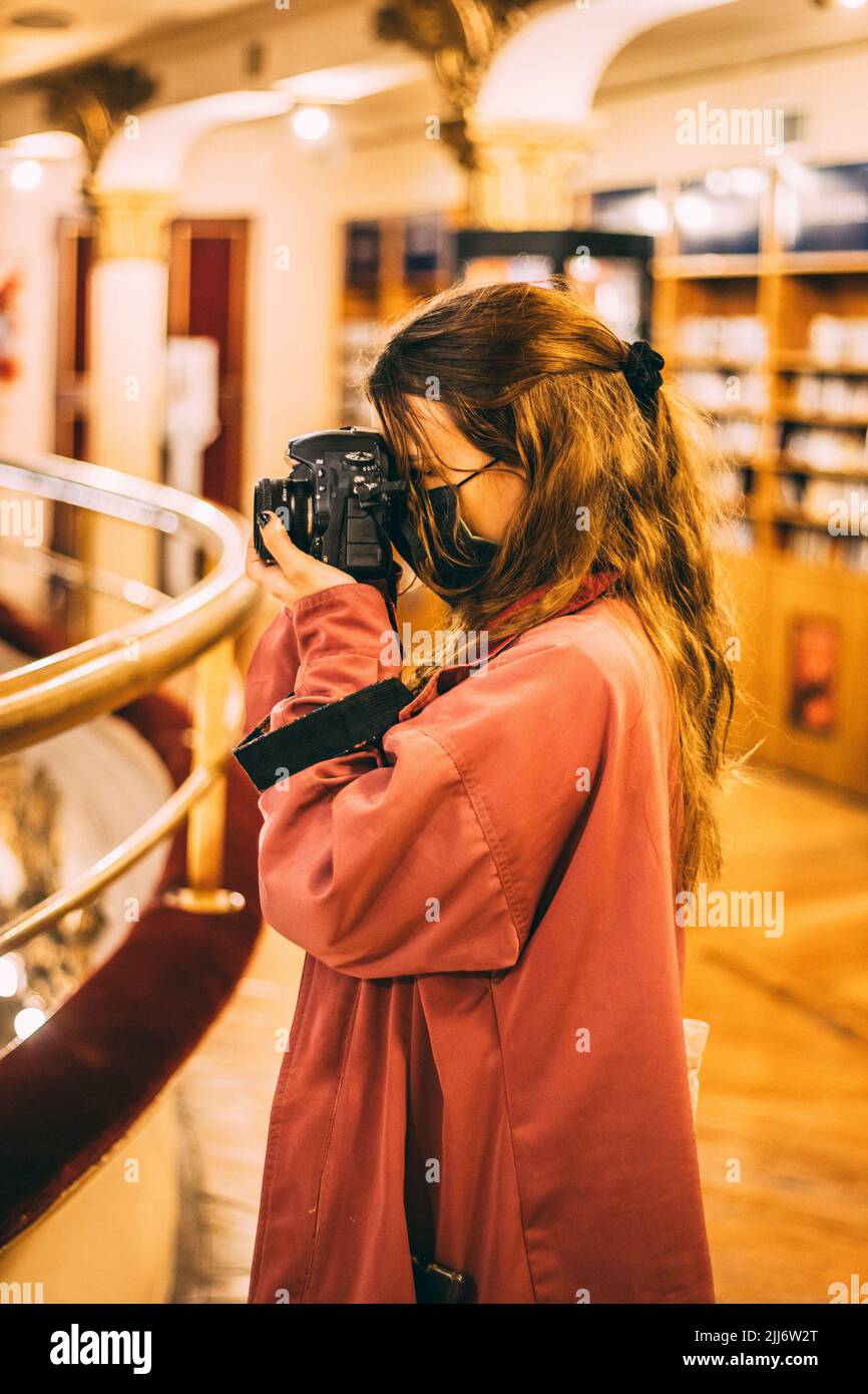 A vertical side view of a female photographer taking a picture wearing ...