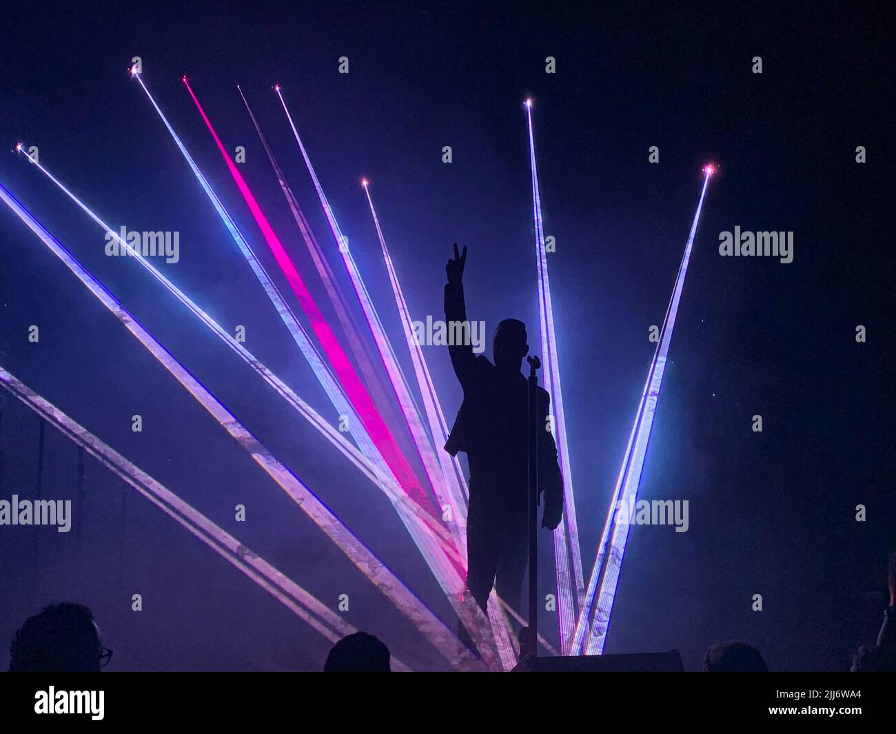 A silhouette of male singer performing on the stage with laser show ...