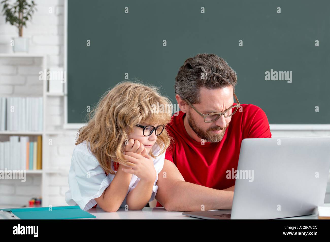 School teacher and child pupil learning at laptop computer, studying ...