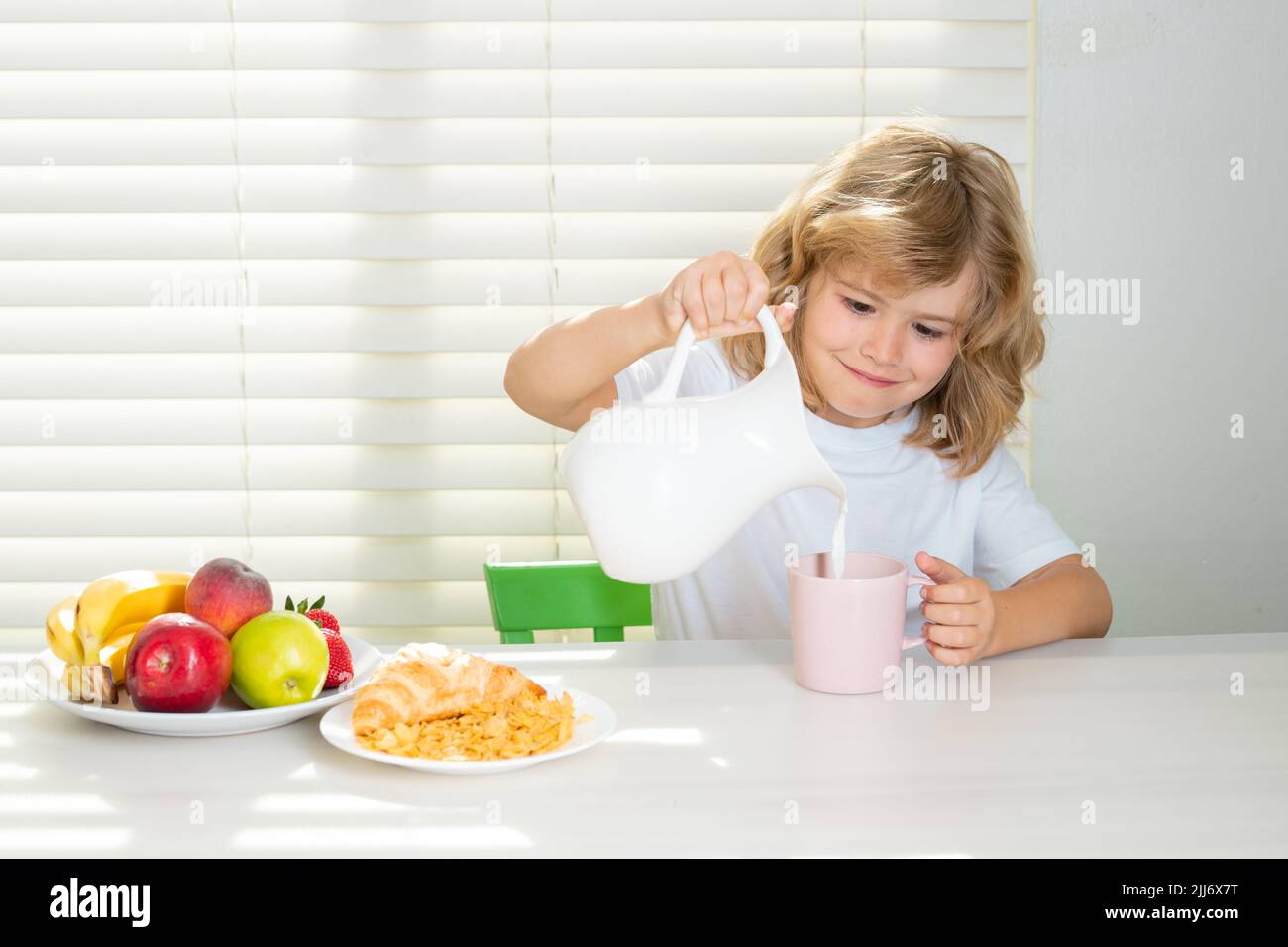 School chil pouring whole cows milk for breakfast. Portrait of child ...