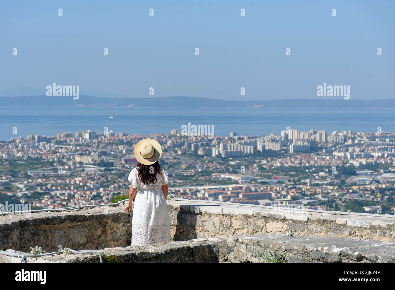 The rear view of a woman standing at Klis fortress overlooking the city of Split, Croatia Stock ...