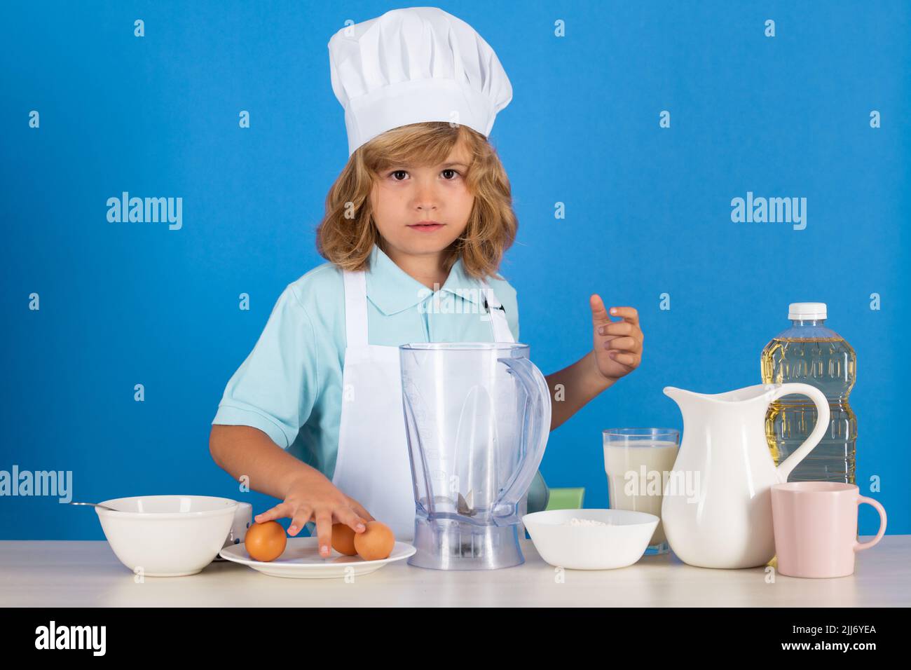Child wearing cooker uniform and chef hat preparing vegetables on ...