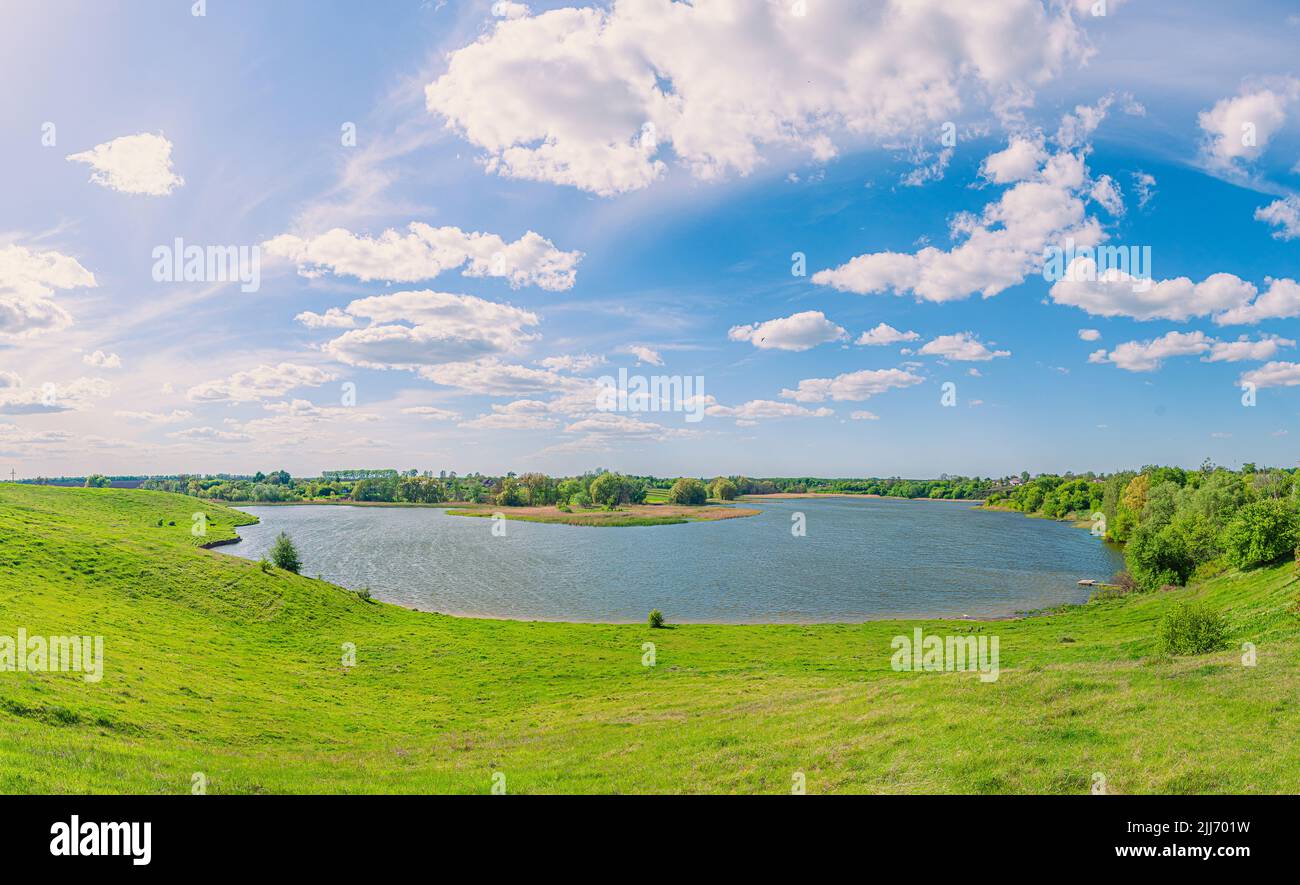 A beautiful lake in the middle of green hills under a blue sky with ...
