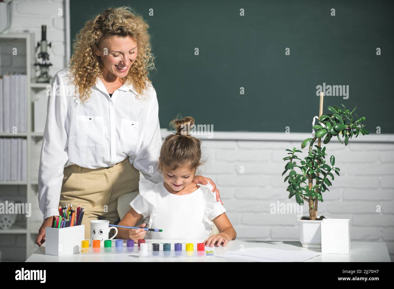 Schoolgirl drawing with teacher. Children from elementary school study ...