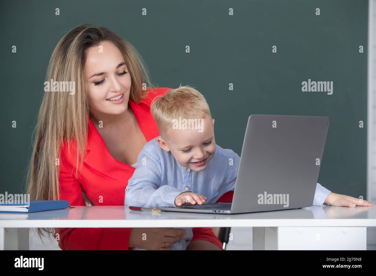 School child using laptop. Elementary school teacher and pupil in ...