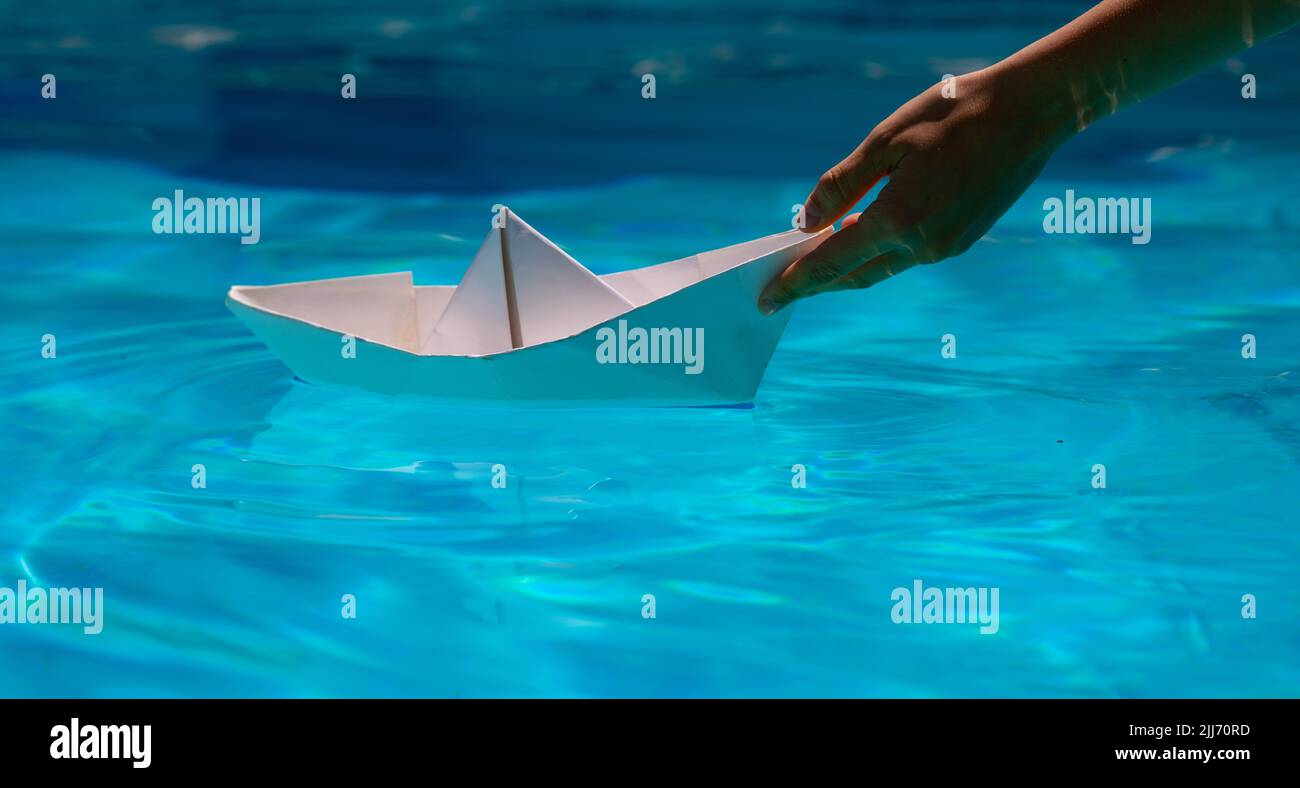 Paper boat with hand. Paper boat sailing on blue water surface. Origami ...