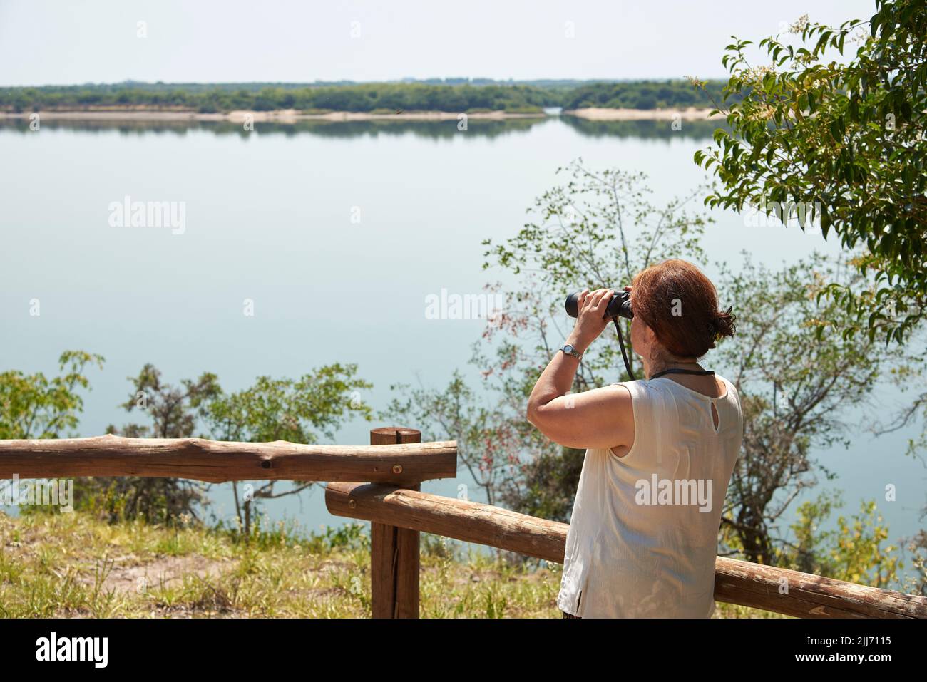 Hispanic mature woman looking through binoculars from a lookout point ...