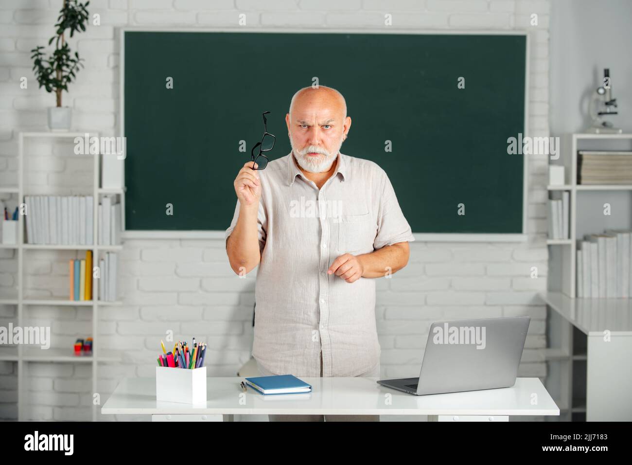Portrait of confident caucasian senior teacher in classroom. Middle ...