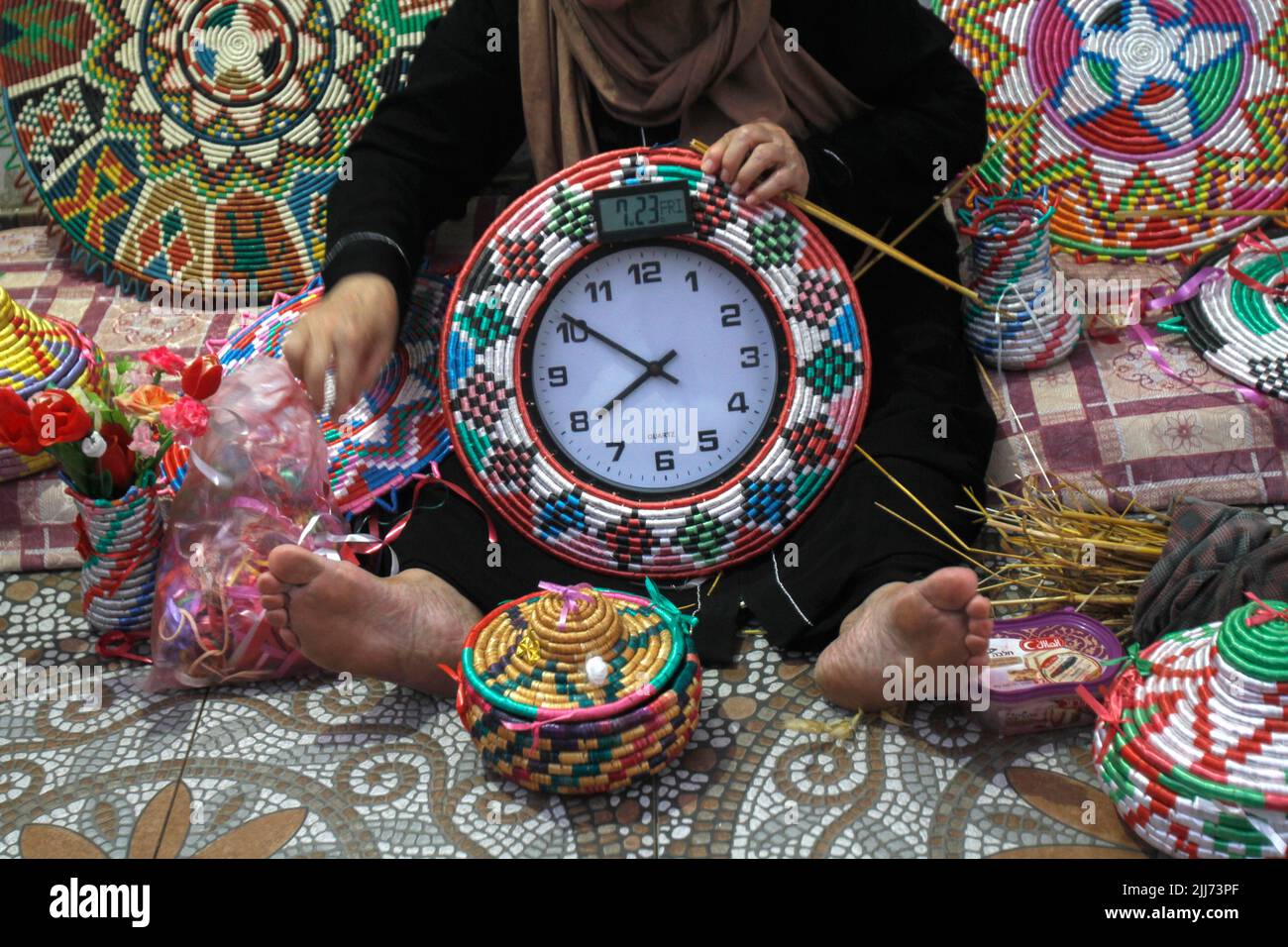 An elderly lady weaves crafts from straw to be sold at the Palestinian ...