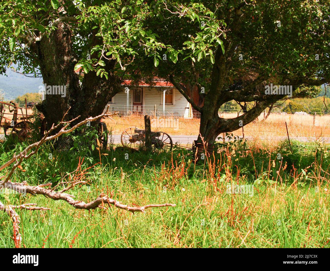 Rustic rural scene with old farm house and wagon wheels framed by large ...
