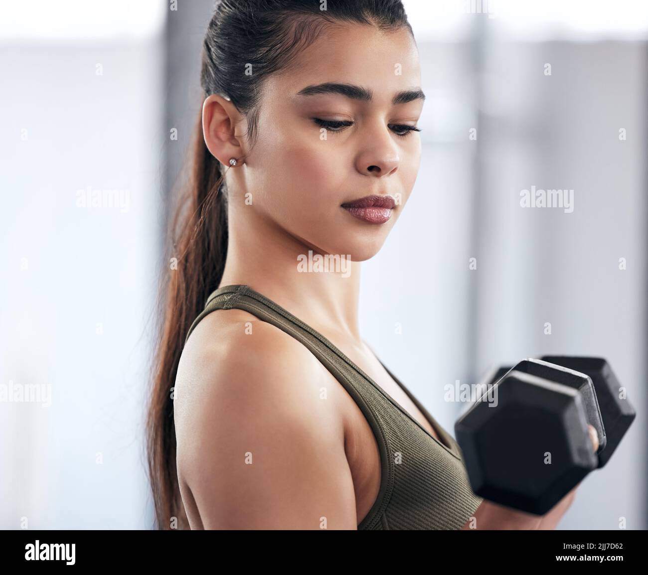 Mind over matter. a young woman working out with dumbbell weights in a ...