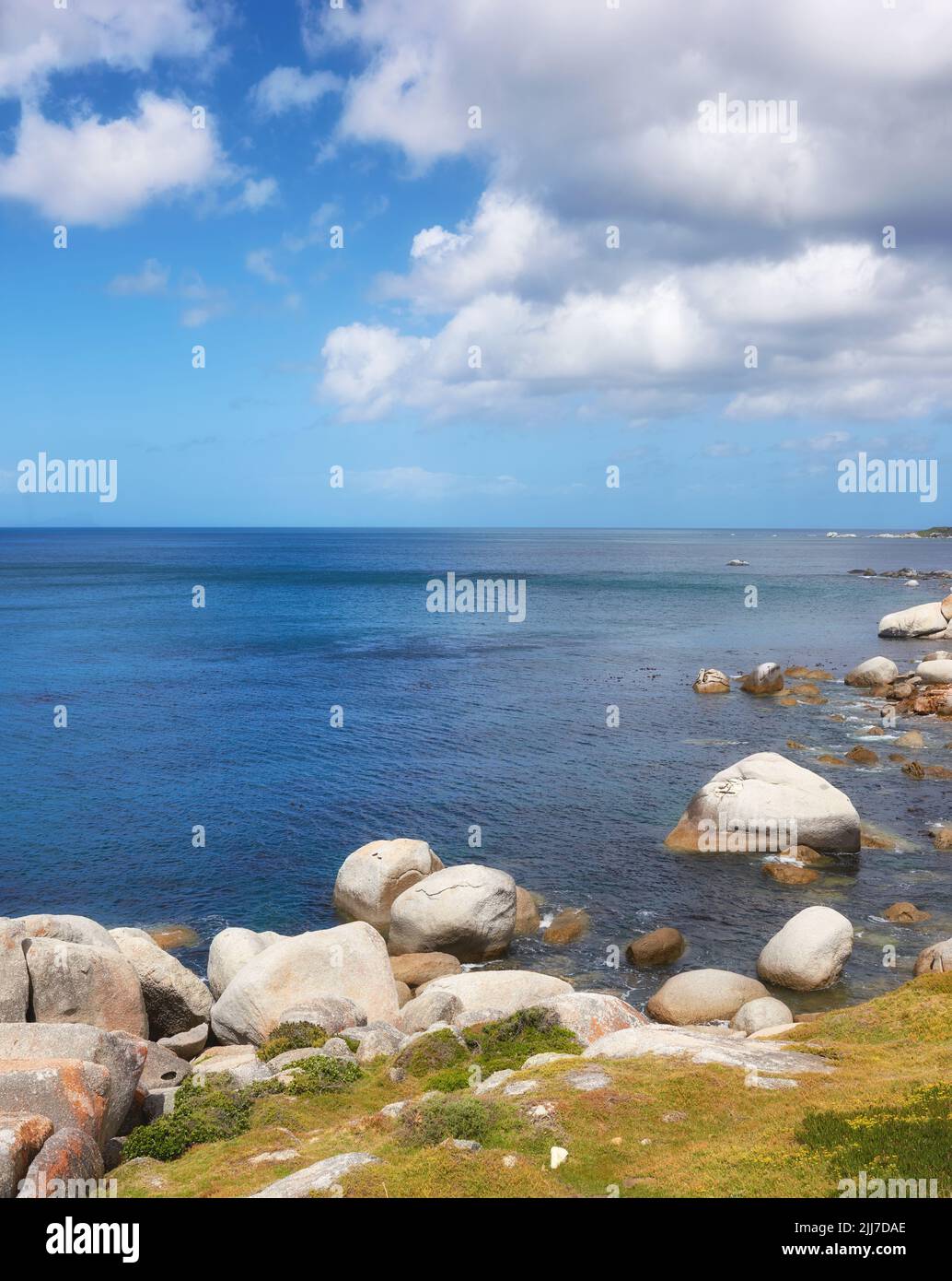 Scenic ocean view of beach with rocks or boulders and sea water washing ...