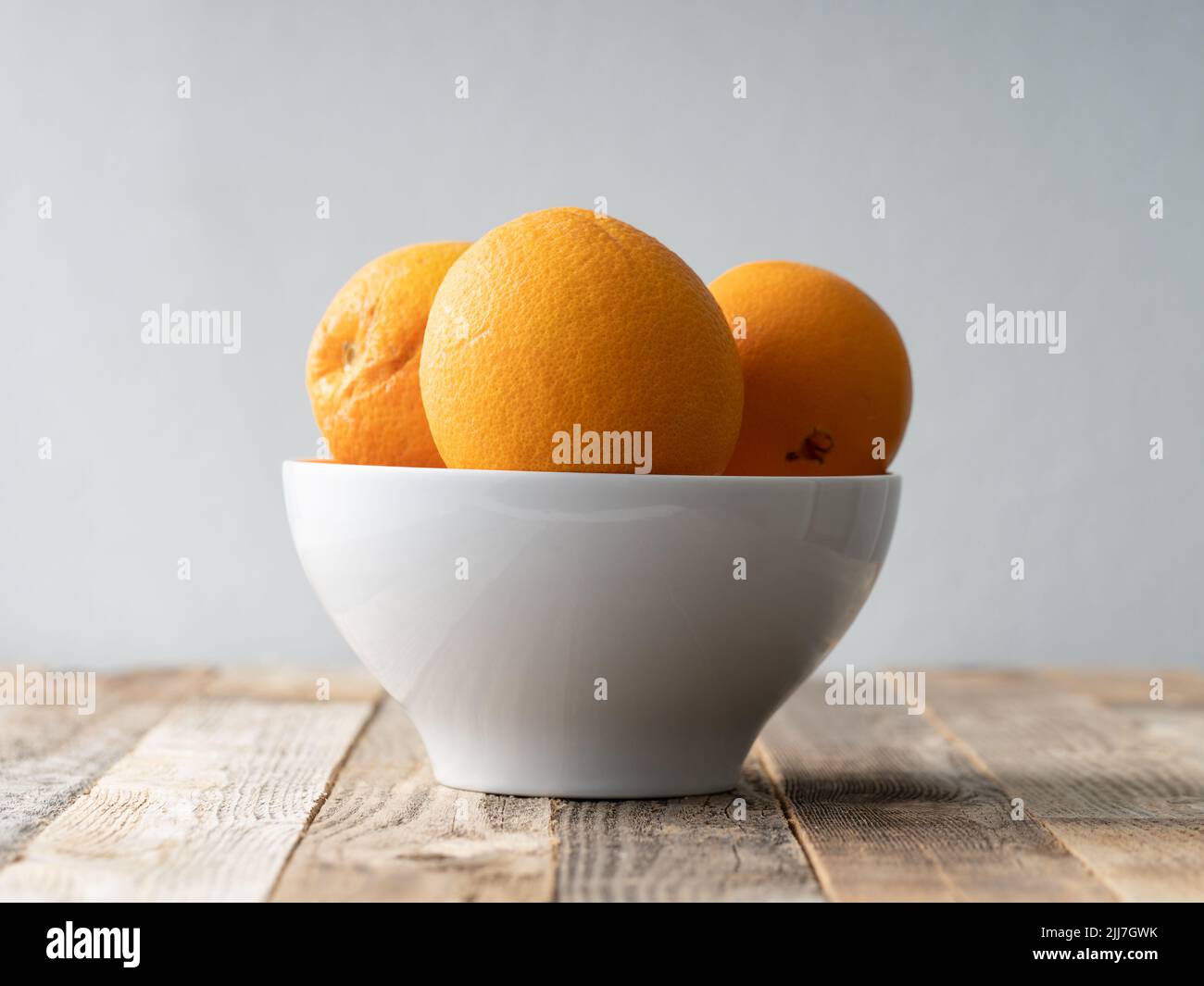 White bowl overflowing with navel oranges on wood table Stock Photo - Alamy
