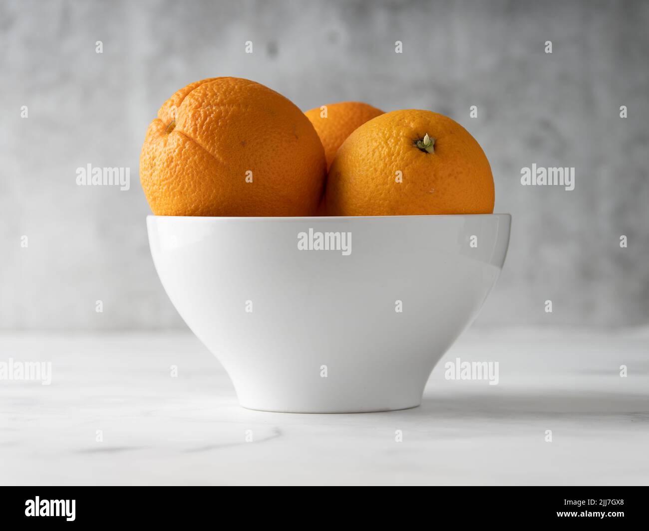 White bowl overflowing with navel oranges on wood table Stock Photo - Alamy