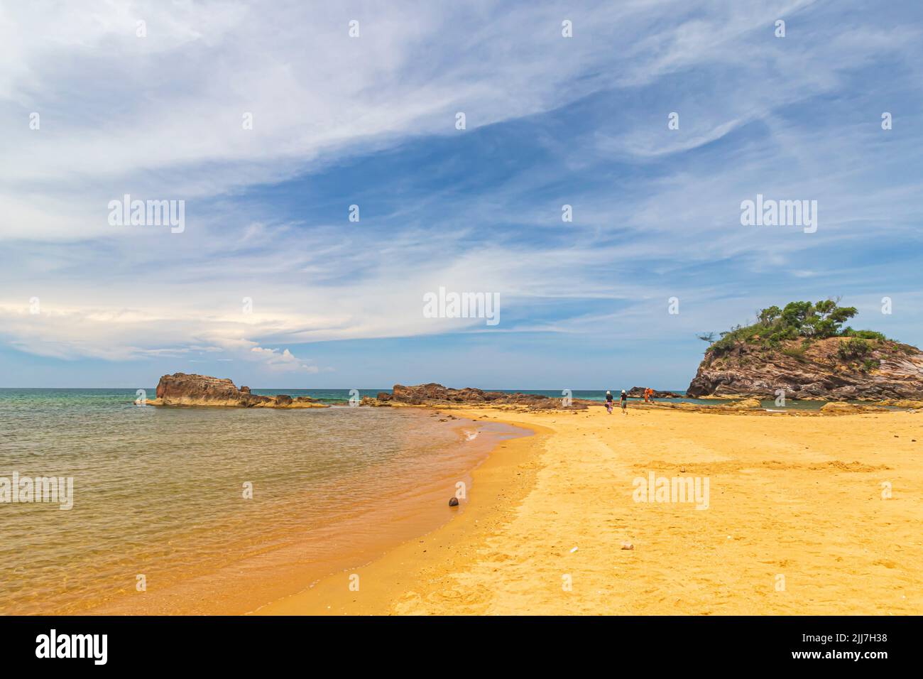 A view of the beach with golden sand stretching out and rock formations ...