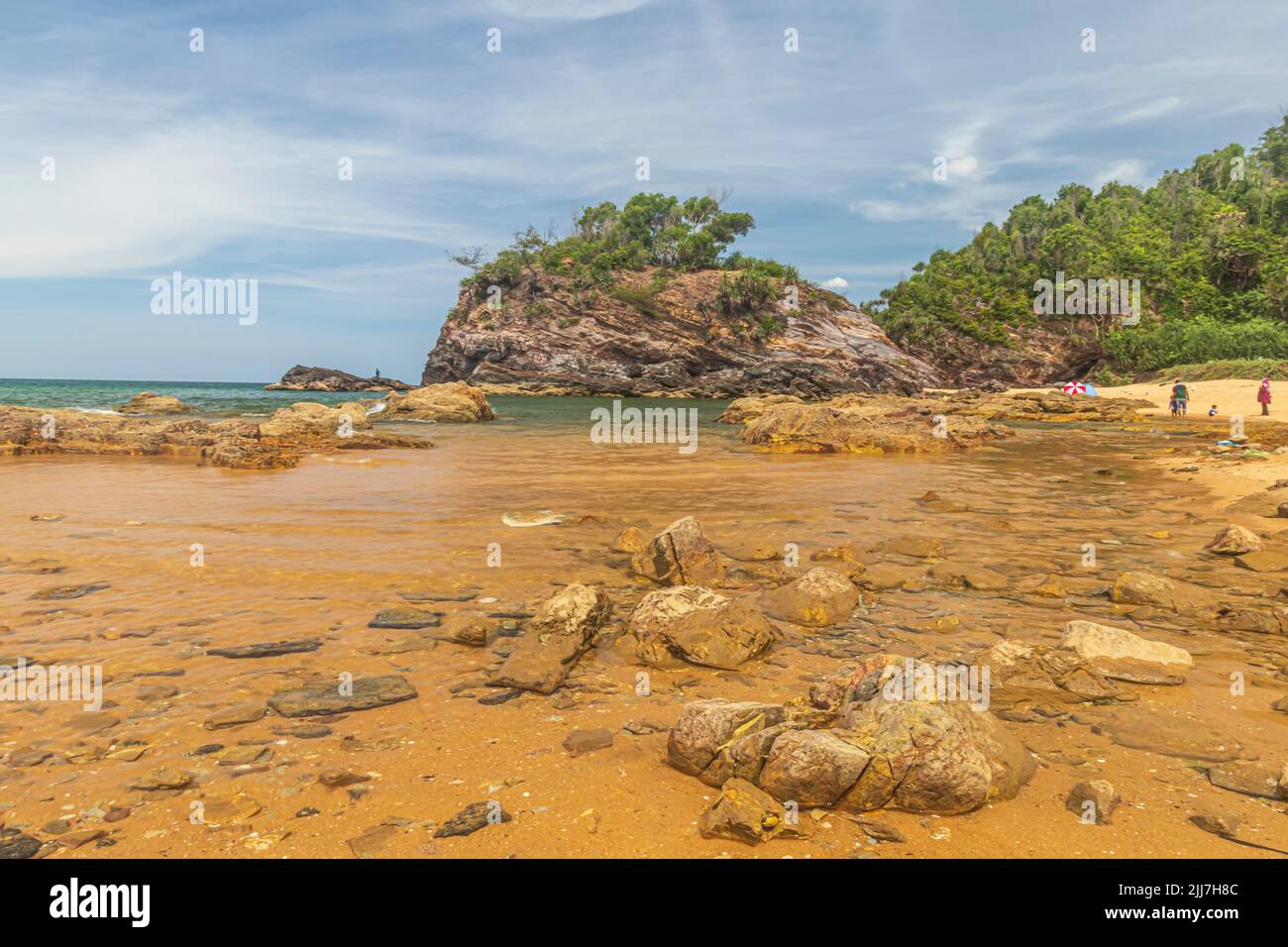Beach view with rock outcrops in shallow water by the beach and rock ...