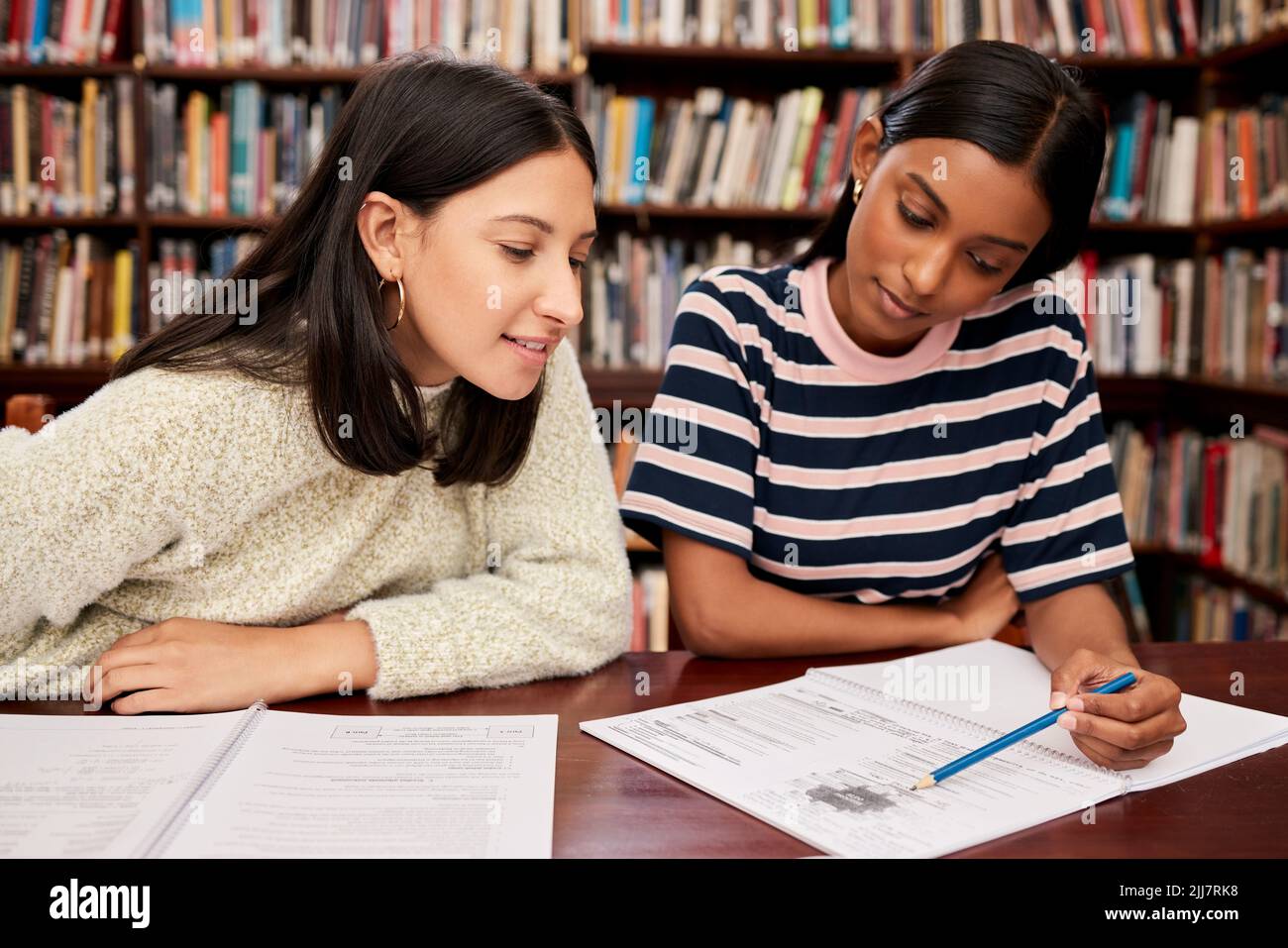 Whats the next question. two young female students studying together in ...