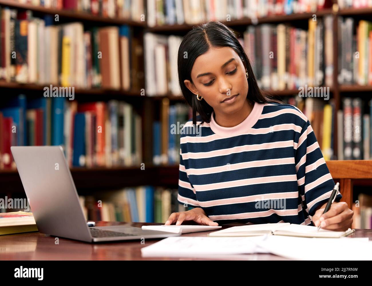 Taking notes makes revising easier. a young female student studying in ...