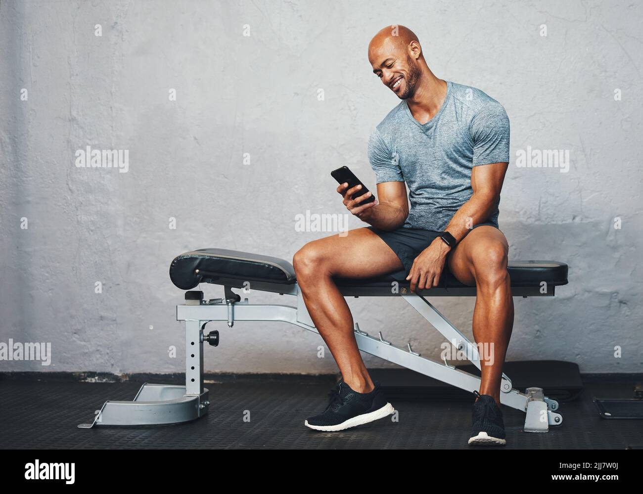 Catching a break with his connections. a muscular young man using a cellphone in a gym Stock ...