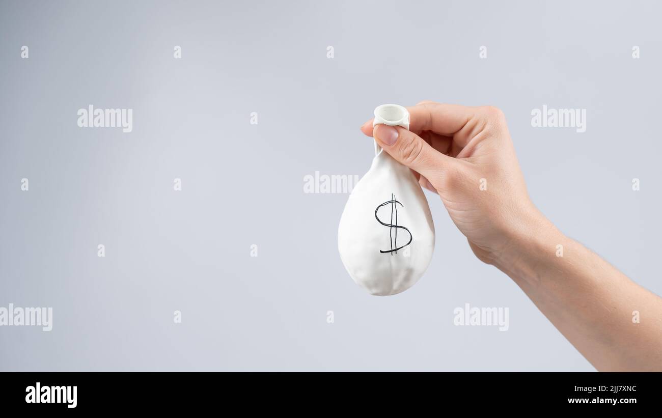 A woman is holding a deflated balloon with a dollar sign. The concept ...