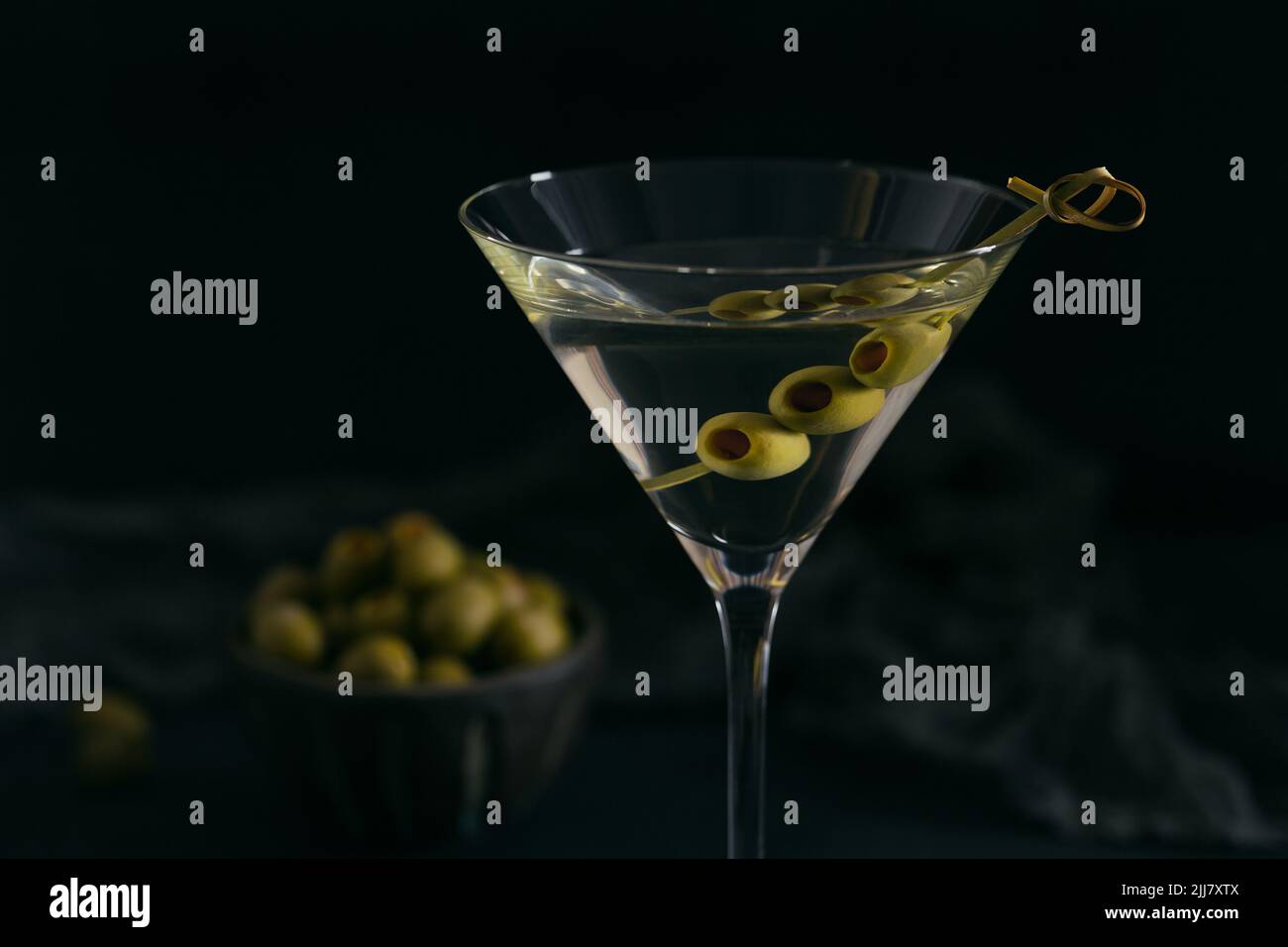 Glass of classic dry martini cocktail with olives on dark stone table ...