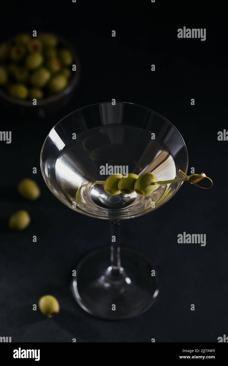 Glass of classic dry martini cocktail with olives on dark stone table ...