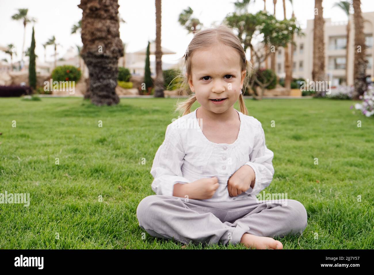 child sitting on the grass, palm trees on the back. Rest in Egyptian ...