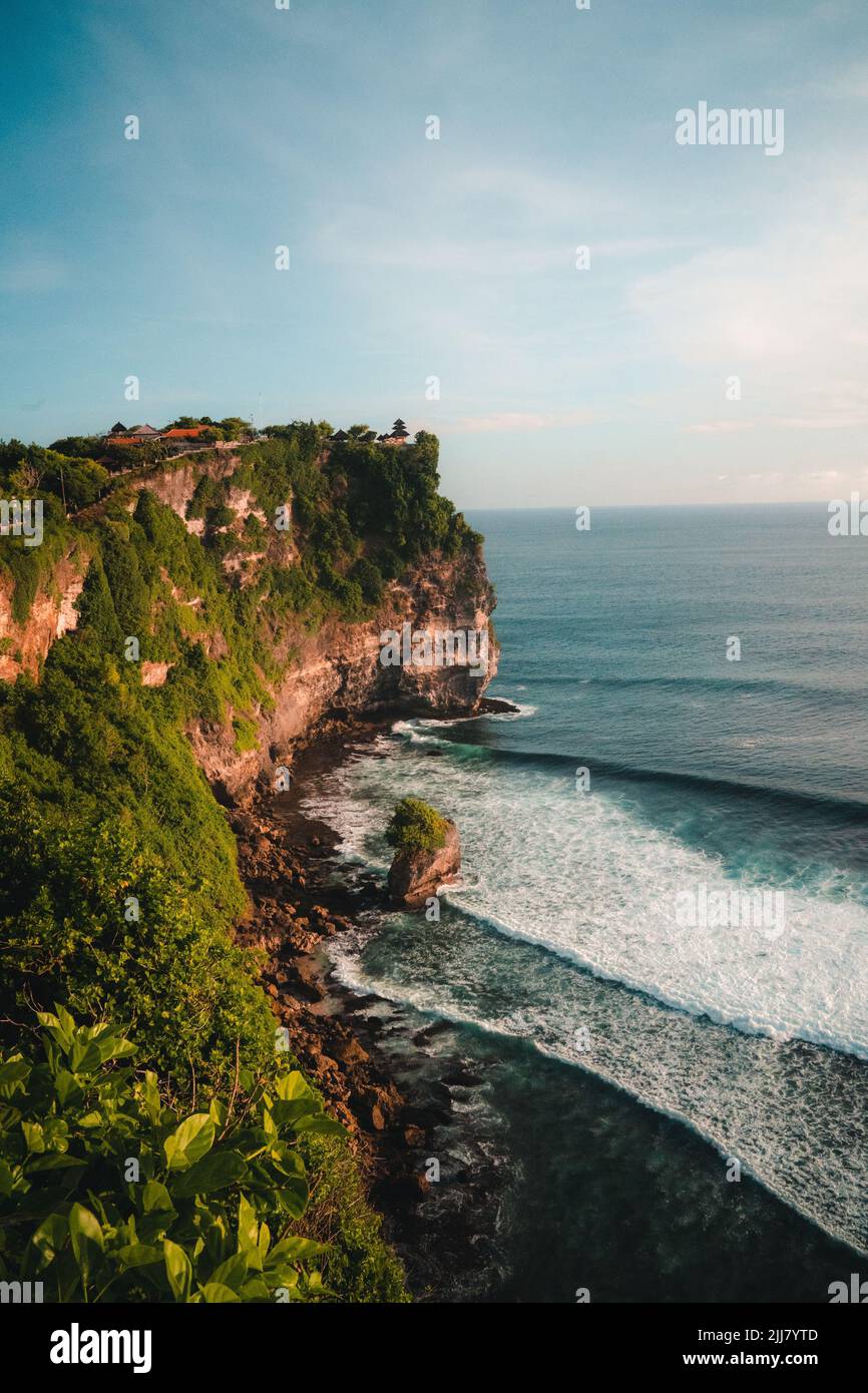 The soft ocean waves with foam on the rocks by the huge cliff of ...