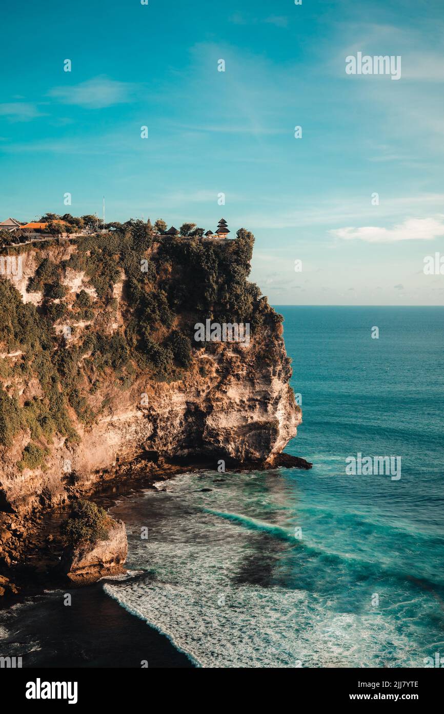 The soft ocean waves with foam on the rocks by the huge cliff of ...