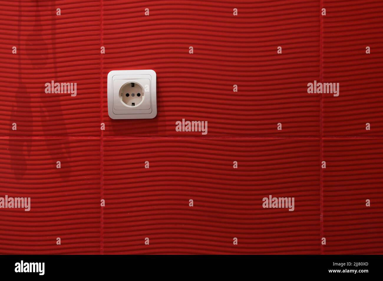 White socket installed in a red-tiled wall. Abstract bathroom ...