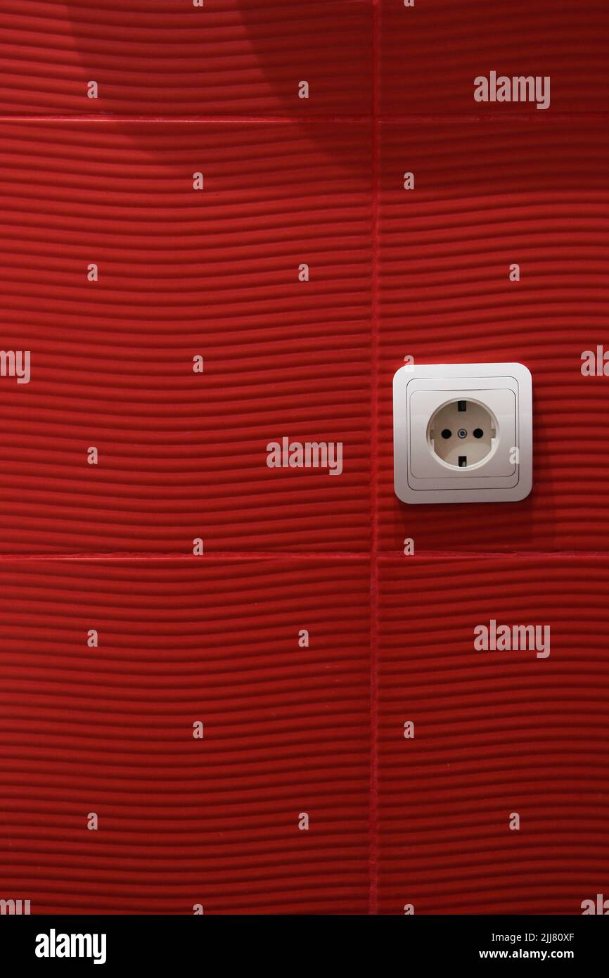 White socket installed in a red-tiled wall. Abstract bathroom ...