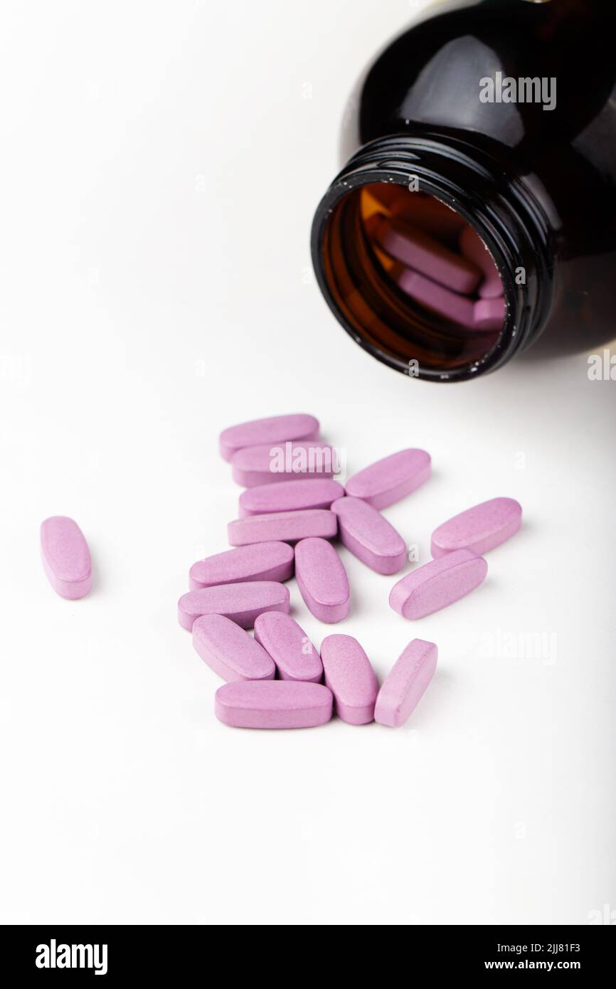 Pink medical pills and tablets spilling out of a drug bottle ...