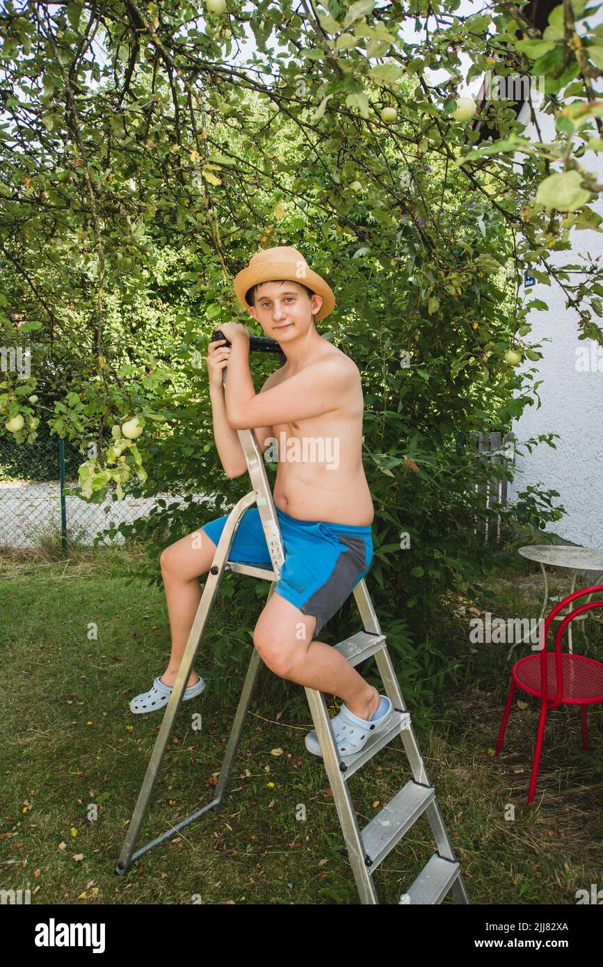 Teenager sitting on a ladder under an apple tree Stock Photo - Alamy
