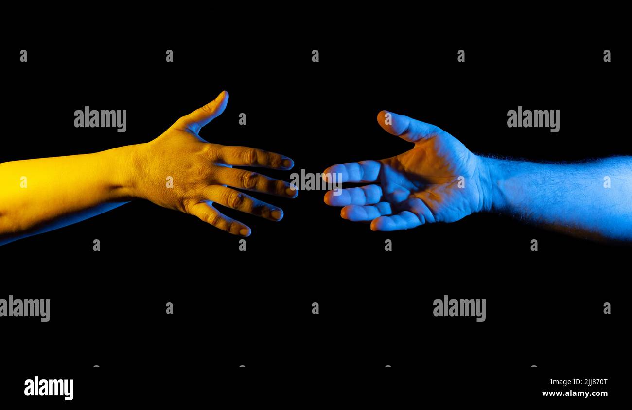 Two hands, male and female, one in yellow one in blue light reaching ...