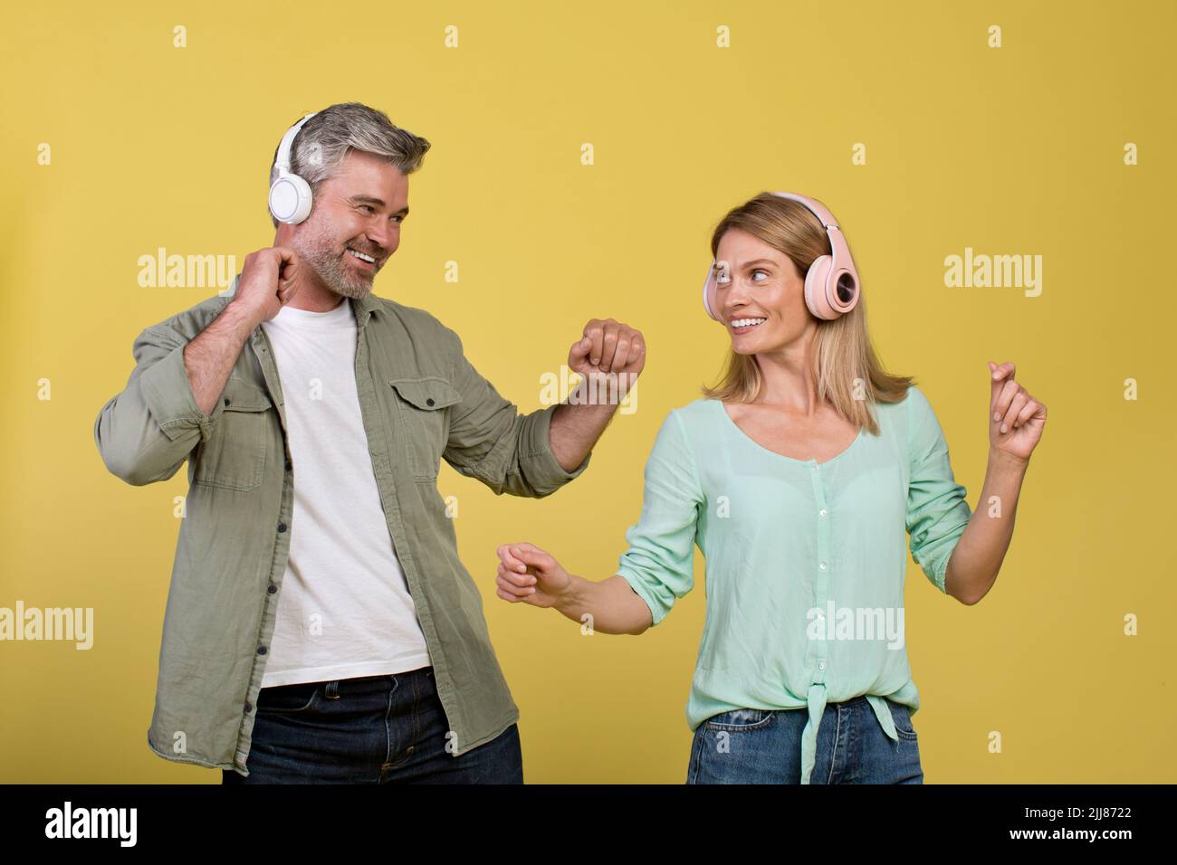 Enjoy music together. Happy middle aged spouses in wireless headphones ...