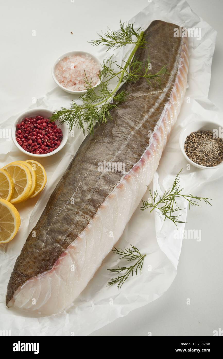 High angle of raw fish fillet and various seasonings placed on white ...