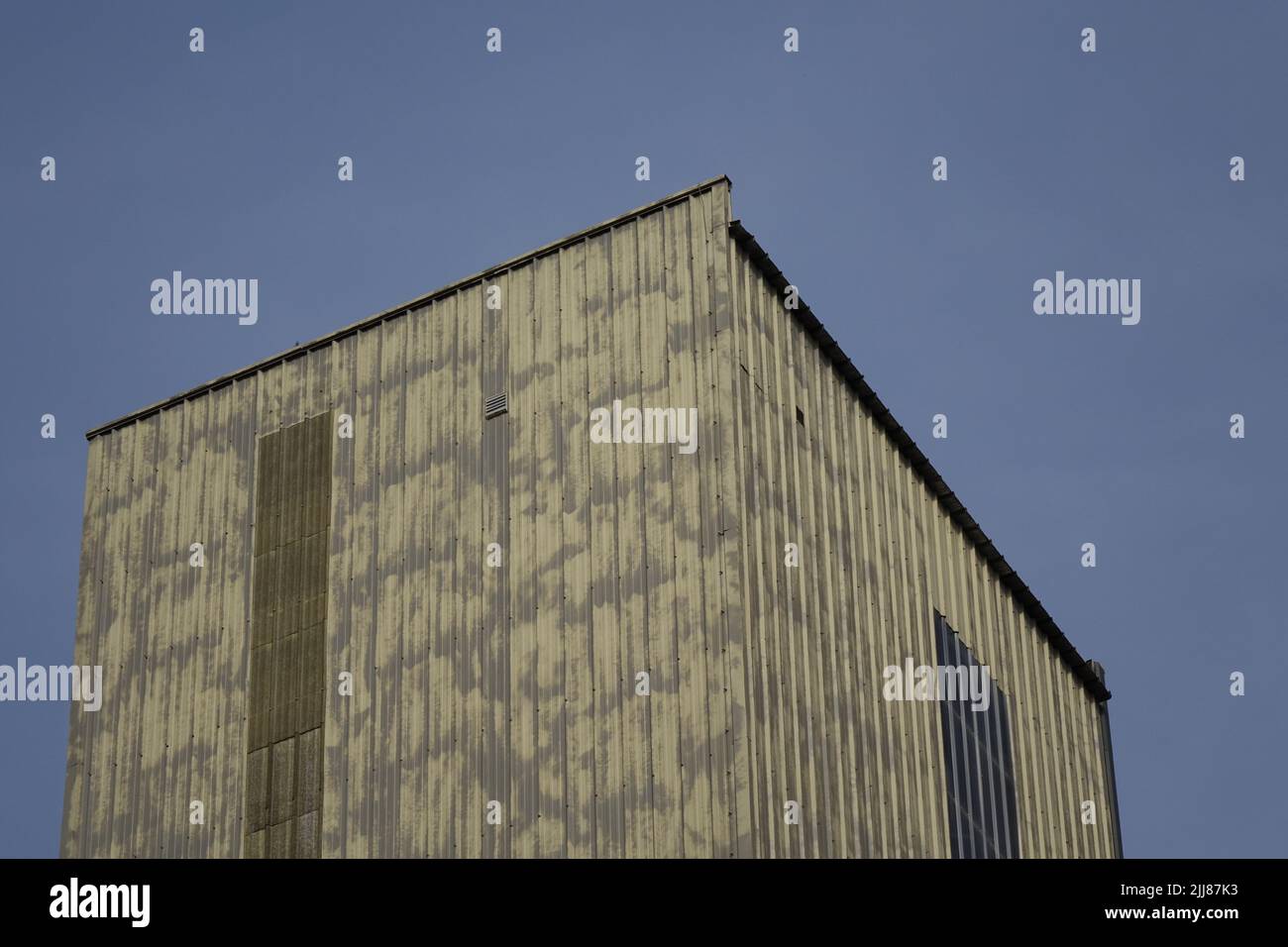 Cubic metal tower of factory building under blue spring sky, concept ...