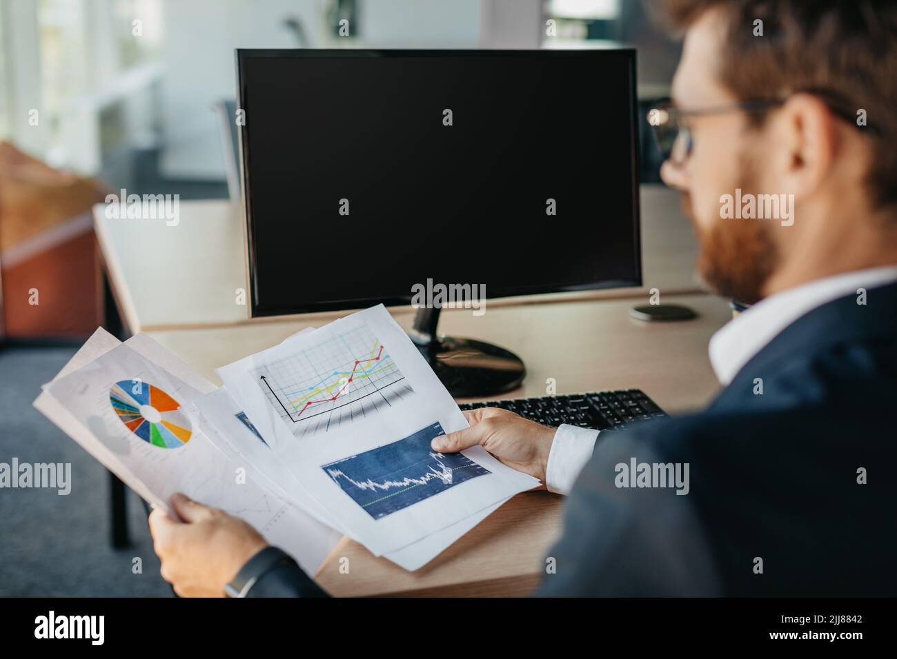 Successful entrepreneur reading financial reports, sitting at workplace ...