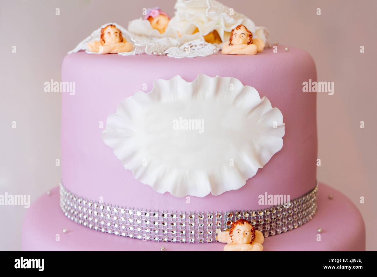 Two-tiered pink cake with a place for an inscription and little angels ...